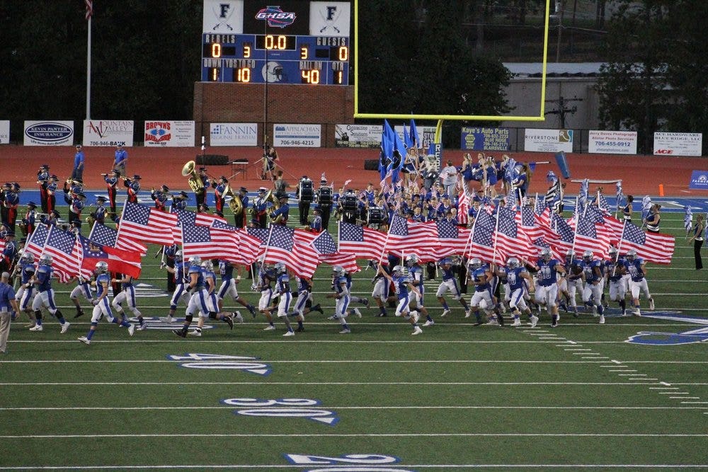 EPIC! Entire high school football team runs onto field with American ...