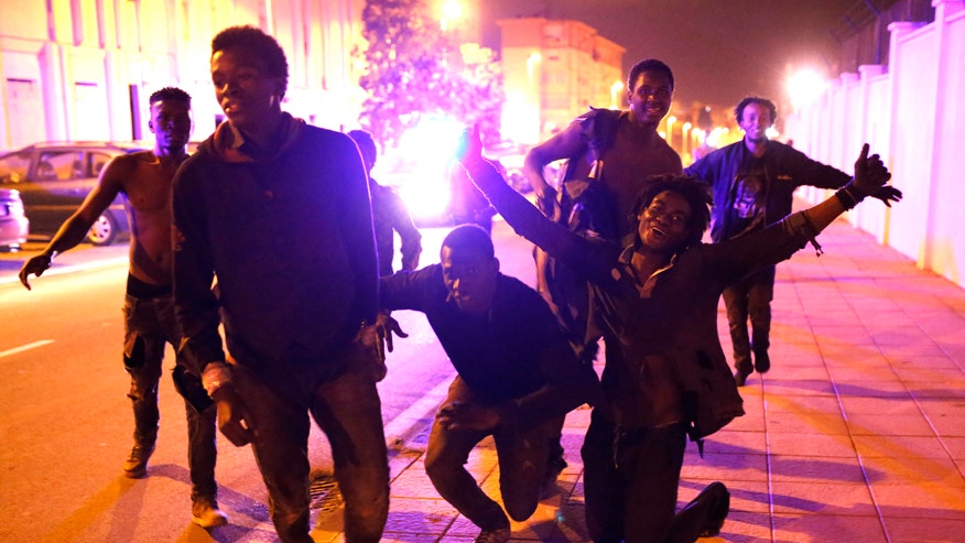Almost 500 migrants smash through border fence into Spanish enclave in ...
